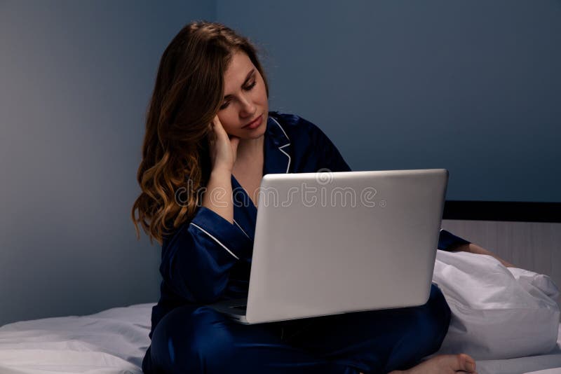 Tired Handsome Female Sitting at Home in the Bed and Working on a ...