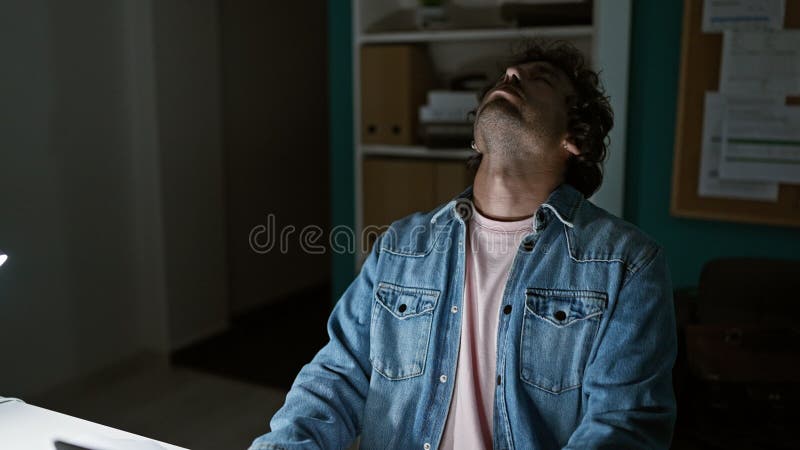 A Tired Hispanic Man in a Denim Jacket Expressing Frustration in a Dark ...