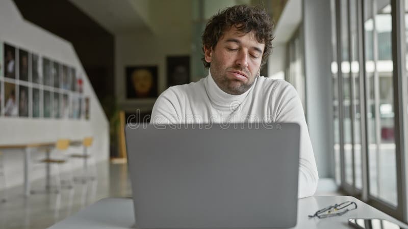 A Tired Hispanic Man in a Modern Office, Resting His Head on His Hand ...