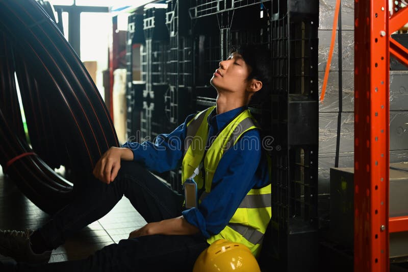 Tired Male Warehouse Worker Leaning Against Rack, Taking Break and ...