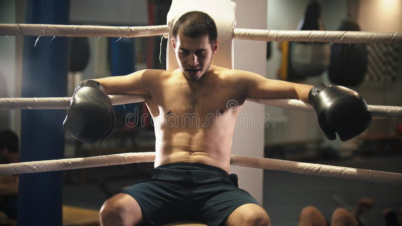 A Tired Man Boxer Sitting on the Ring in the Corner while Break Stock ...