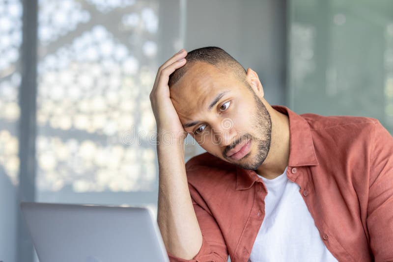 A Tired Man Leans His Head on His Hand while Looking at a Laptop ...