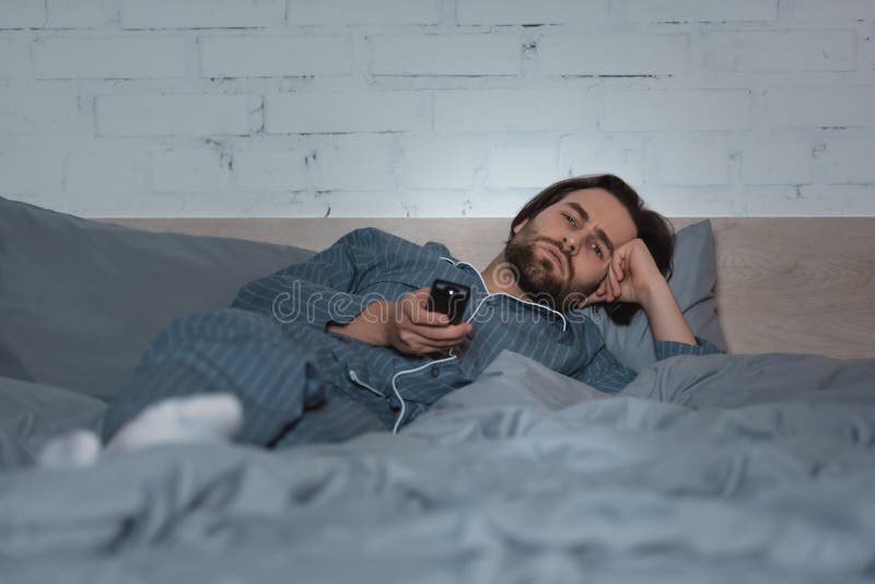 Tired Man in Pajama Holding Remote Stock Image - Image of bedding ...