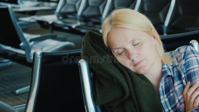 Tired Passenger Sleeps At The Airport Terminal Waiting For Your Flight