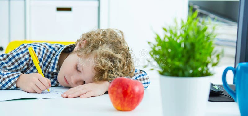 Tired Schoolboy Writes in a Notebook during Lesson Lying on a Table ...