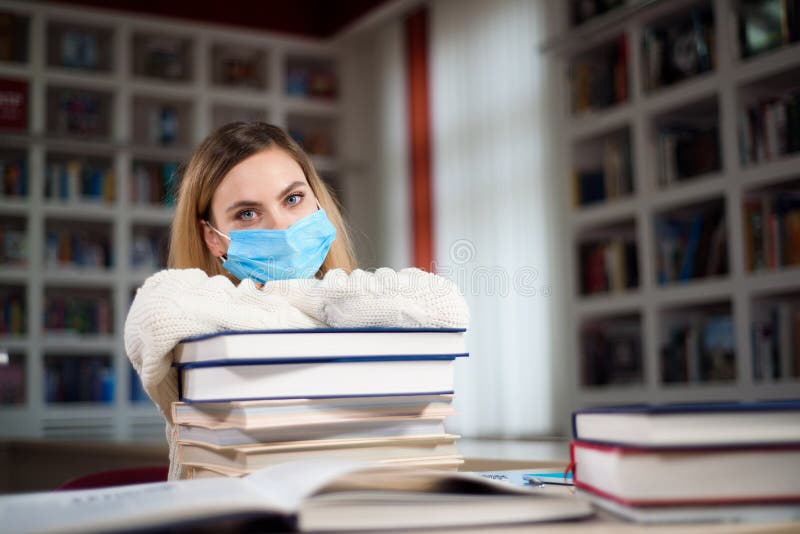 A Tired Student in a Protective Mask for the Face Studying in the ...