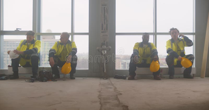 Tired Team of Builders Sitting on Heaters and Resting at Construction ...