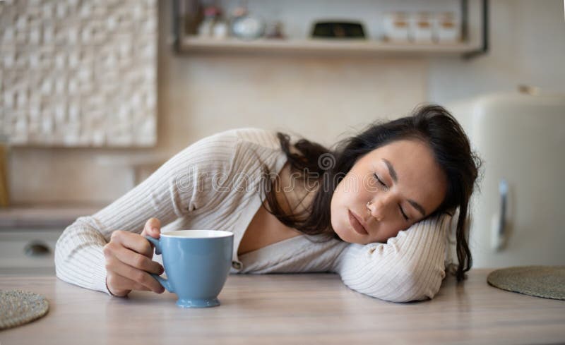 Tired Woman with Coffee Cup Sleeping on Table in Modern Light Kitchen ...