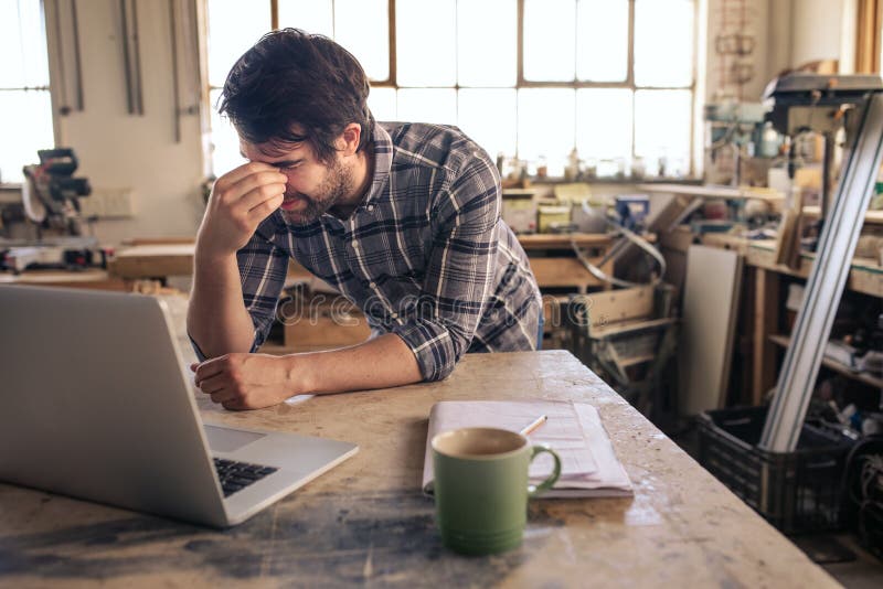 Tired Woodworker Working on a Laptop in His Carpentry Studio Stock ...