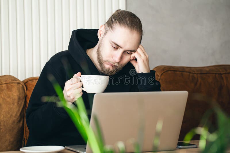 Tired Young Man Working on a Laptop with a Cup of Coffee. Stock Image ...