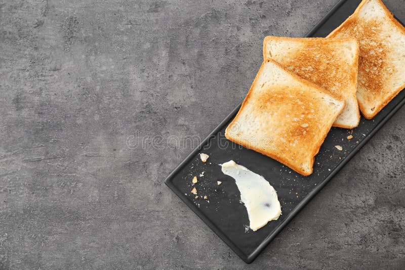 Toasted Bread Served with Butter on Black Plate, Top View Stock Photo ...