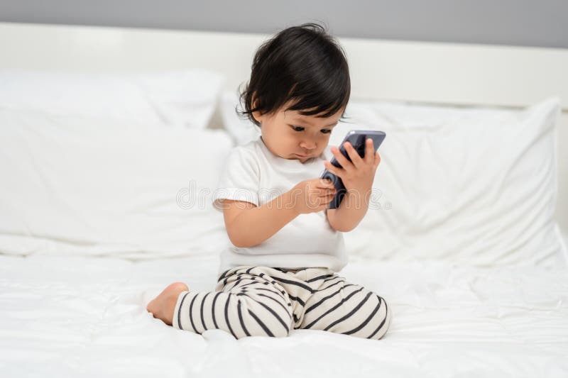 Toddler Baby Using and Watching Smartphone on Bed Stock Image - Image ...