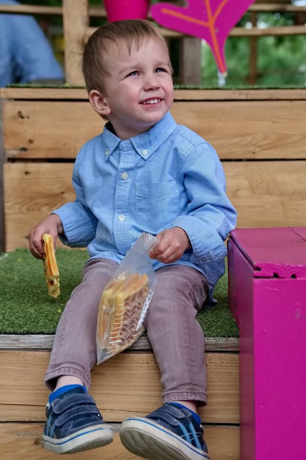 Toddler Sitting on the Bench and Eating Cookies Stock Photo - Image of ...