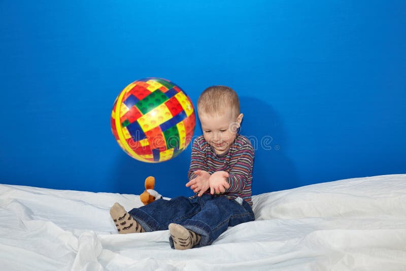 Toddler Throws the Ball with His Hands on a Blue Background Stock Image ...