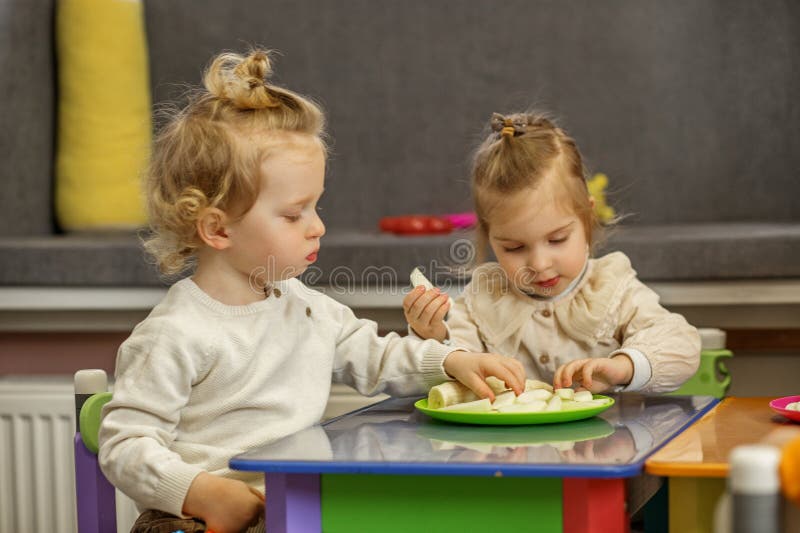 Toddlers Sharing Snack Time at Play Table Stock Photo - Image of ...