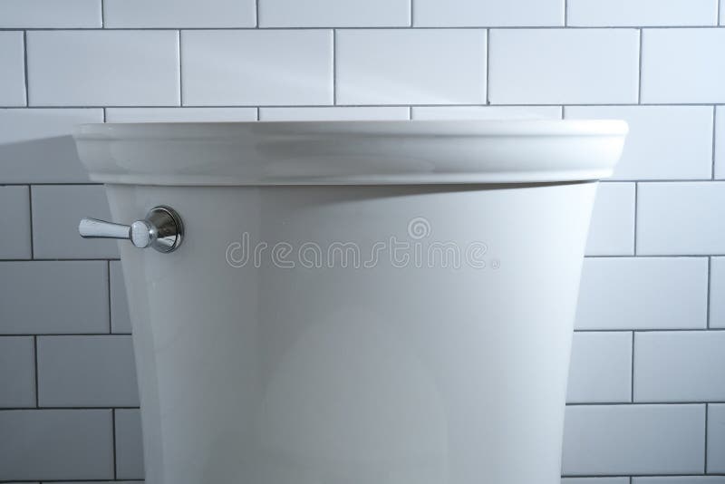 Toilet Tank and Chrome Handle in Front of a White Subway Tile Wall ...