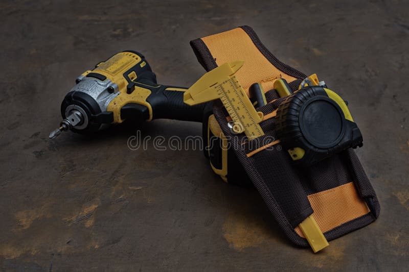 A Tool Belt Holding a Cordless Drill, Caliper, and Tape Measure Lies on ...