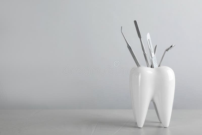 Tooth Shaped Holder with Dentist`s Tools on Light Grey Table. Space for ...
