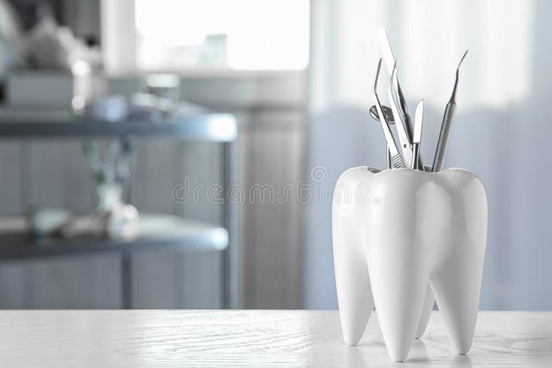 Tooth Shaped Holder with Professional Dentist Tools on Table in Clinic ...