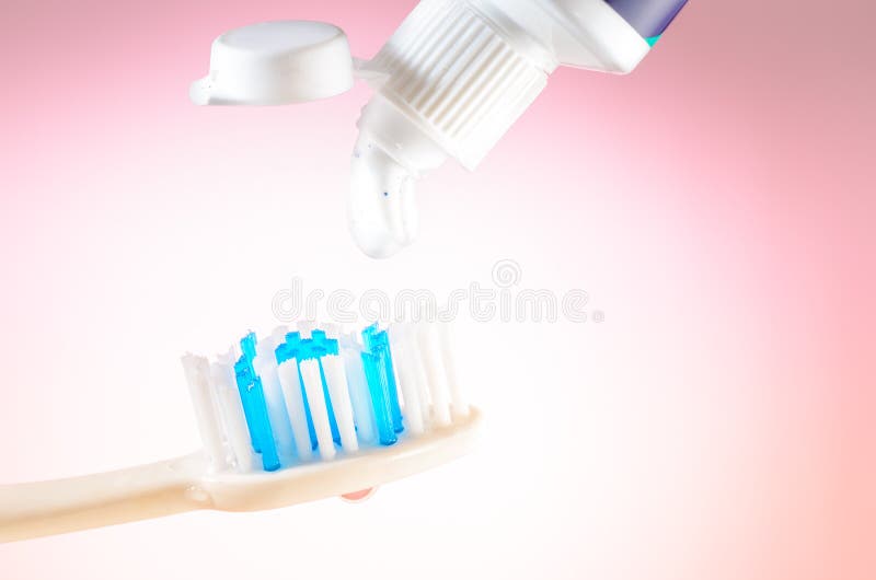 Toothpaste Squeezed from Tube Onto Brush on a Pink Background, Close Up ...