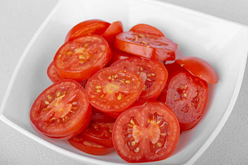 Top Diagonal Close Up View of Sliced Tomatoes in White Bowl on White ...