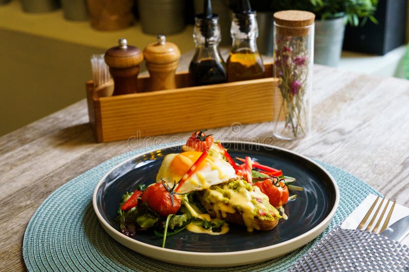 Avocado Toast with Fried Eggs and Vegetables on a Wooden Table Stock ...