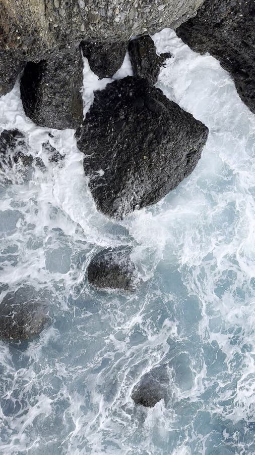 Top-down View of Foamy Waves Crashing the Big Rocks on the Shore at the ...