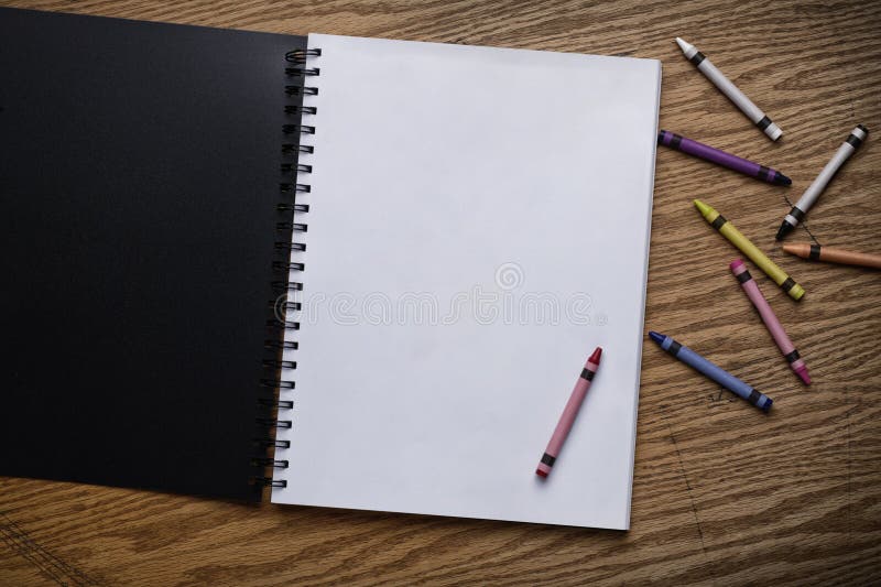 Top View of Assorted Crayons and a Blank Notebook on a Wooden Table ...