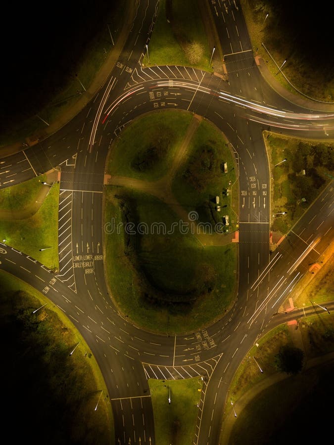 Top View of a Bustling Nighttime Intersection Surrounded by Lush Green ...