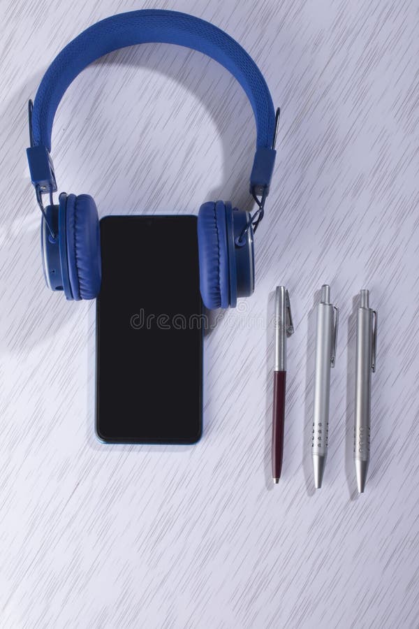 Top View of a Cell Phone with Headphones, Notebooks, and Pens on a ...