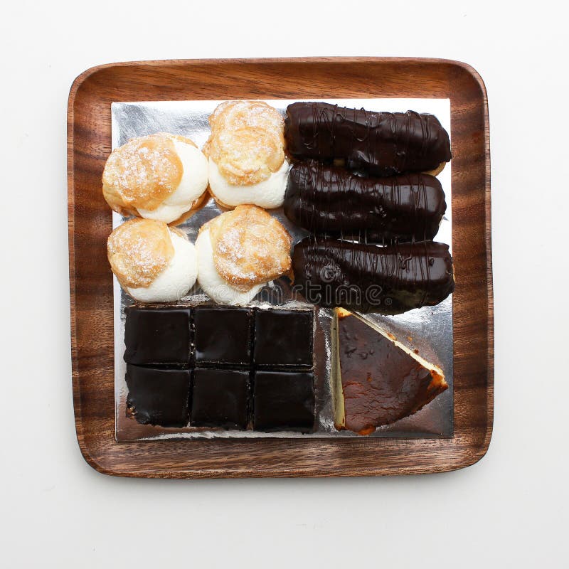 Top View of Choux Pastry Buns, Cheesecake and Eclairs on a Wooden Plate ...