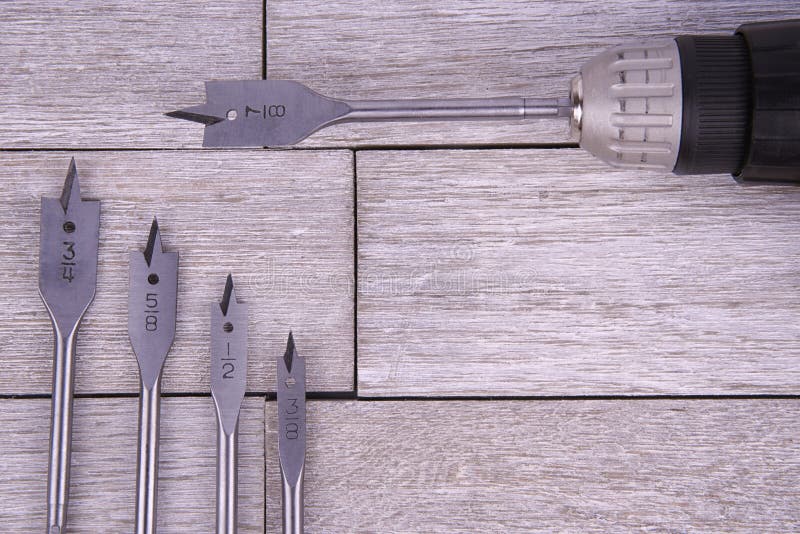 Top View of a Drill and a Set of Metal Bits Lying on a Wooden Surface ...