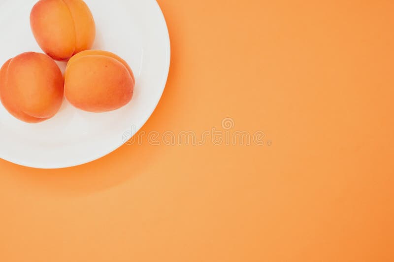 Top View of Fresh Three Apricots on a Plate Isolated on Orange ...