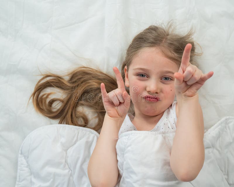 Top View of a Grimacing Little Girl Lying in Bed. Stock Photo - Image ...