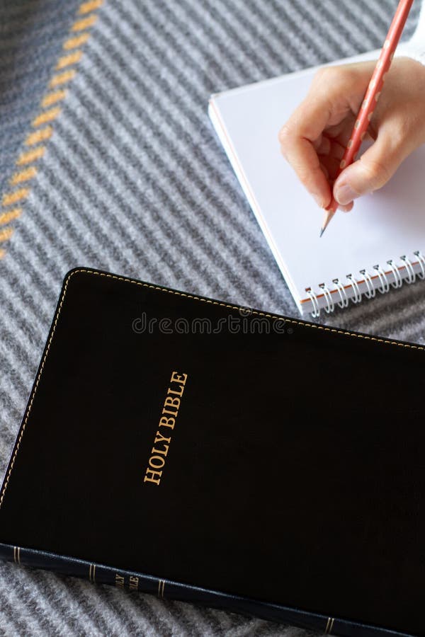Top View of Hand Writing with Pencil, Notebook, and Holy Bible Book on ...
