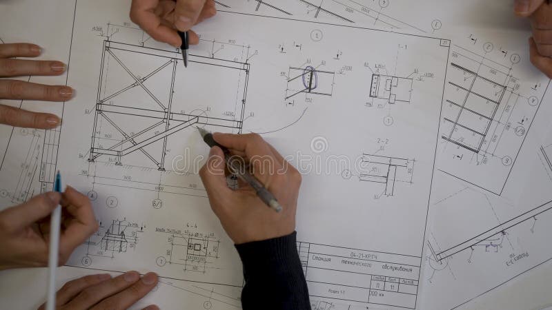Top View of the Hands of Four Colleagues with Blueprints on the Table ...