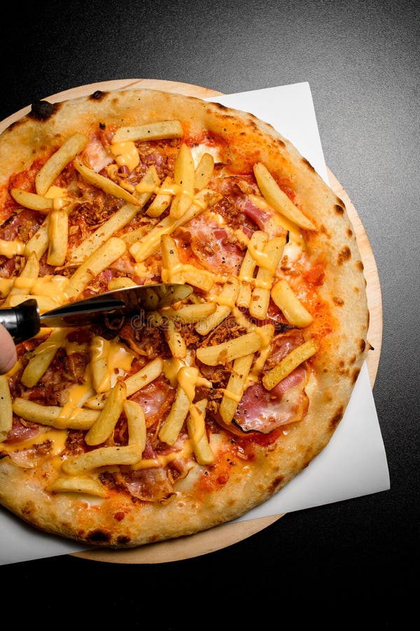 Top View On Hot Pizza With French Fries And Bacon Slices Which Cuts With A Pizza Cutter Stock