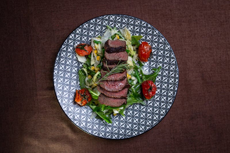 Top View Juicy Sliced Pieces of Beef on a Plate with Herbs and Tomatoes ...
