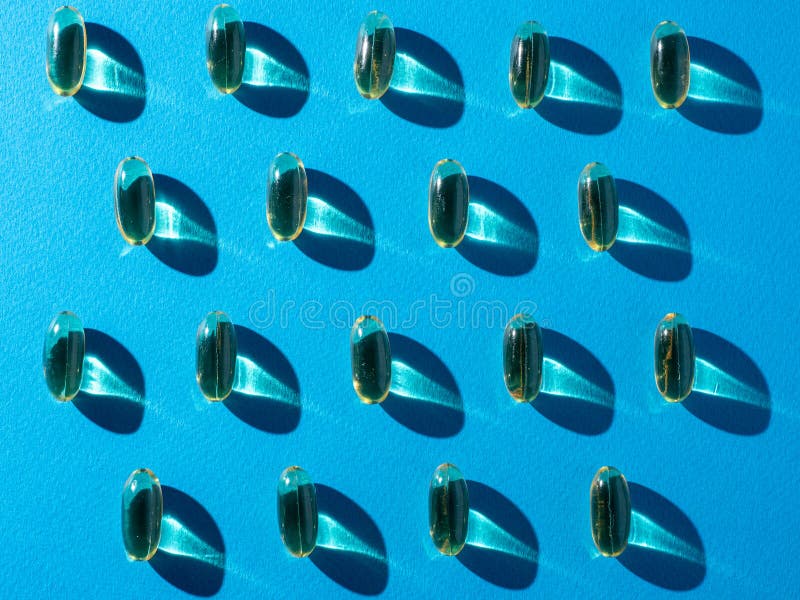 Top View of Omega 3 Capsules Pattern with a Reflection on Blue ...