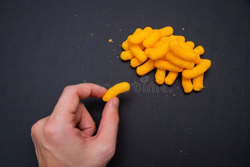 Top View of a Person Taking a Cheese Puff on a Black Surface Stock ...