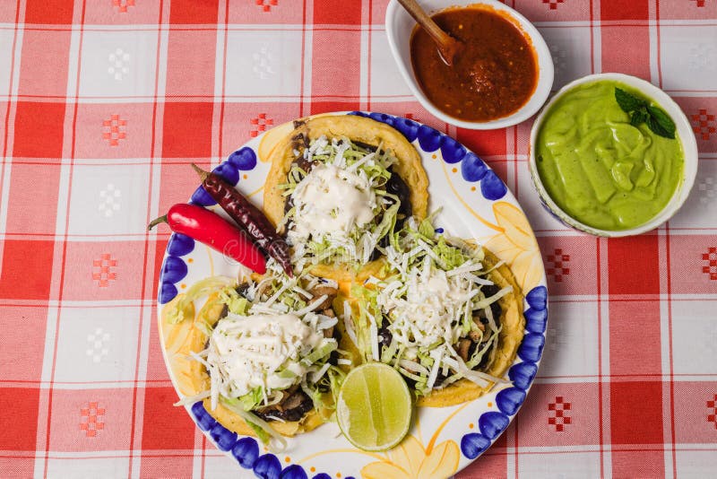 Top View of a Plate of Sopes Next To Dips and Avocado, on a Red ...
