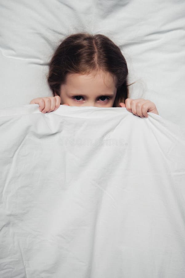 Scared Kid Hiding Under Blanket with Alarm Clock and Looking at Camera ...