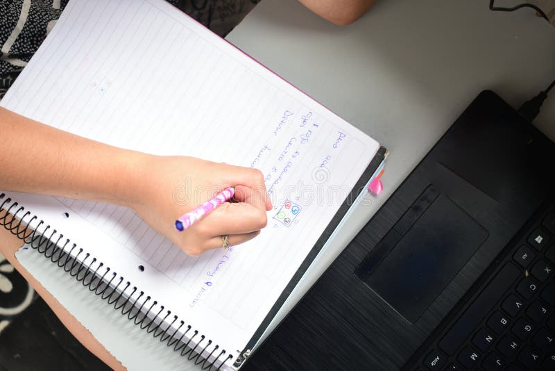 Top View Shot of Female Writing Some Notes in a Notebook from a Laptop ...