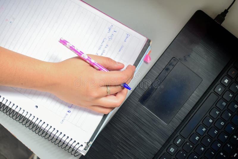 Top View Shot of Female Writing Some Notes in a Notebook from a Laptop ...