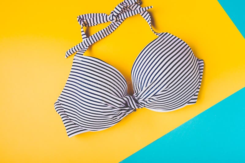 Top View Of Striped Blue And White Swimming Bra On Blue And Yellow Pastel Background Copy Space