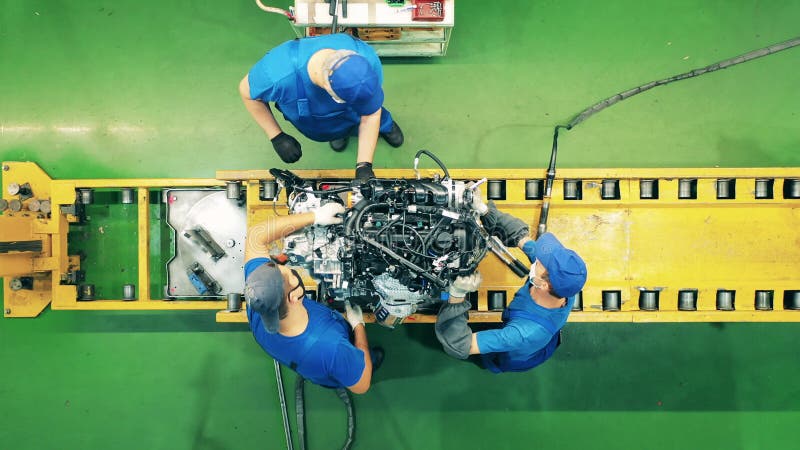 Top View of Three Workers Assembling Car Engine at Car Factory Stock ...