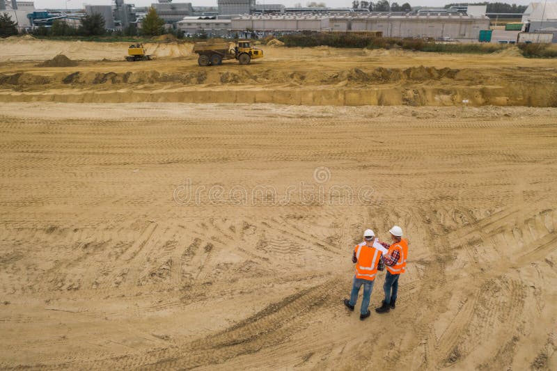 Two Road Construction Workers in Orange Vests and Protective Helmets in ...