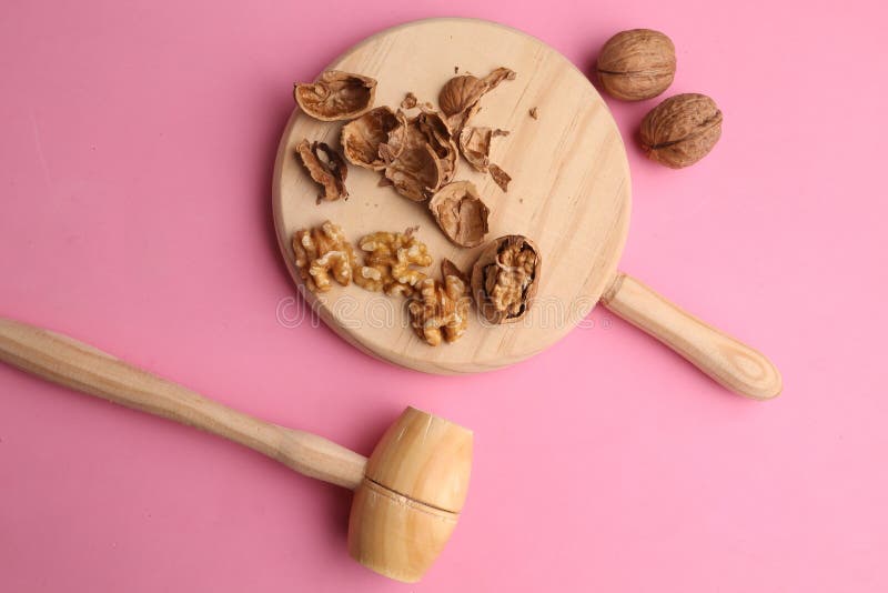 Top View of Walnuts on a Wooden Board with a Hammer on a Pink Surface ...
