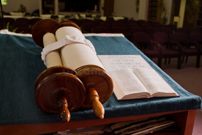 Torah Scroll on Blue Cloth with Empty Synagogue Chairs in Background ...