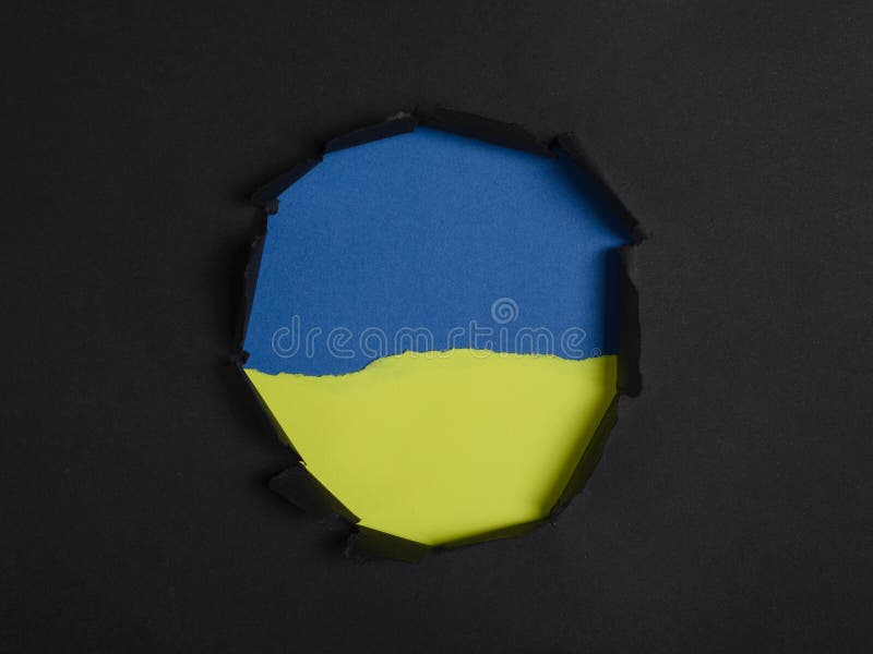 Torn Hole in Black Paper Revealing Blue and Yellow Paper Background ...